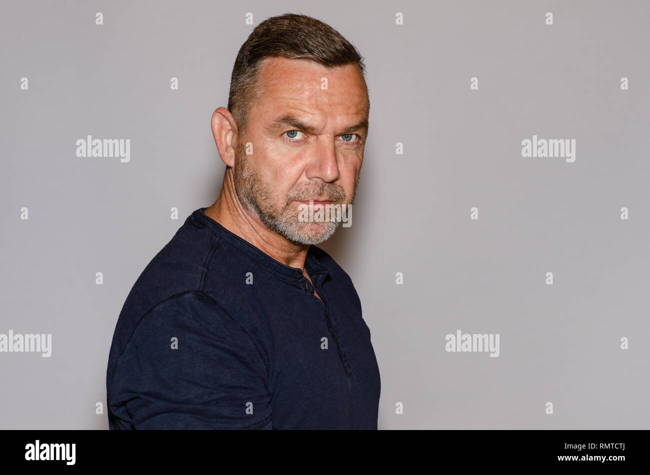 Portrait of serious middle-aged man standing against white background ...