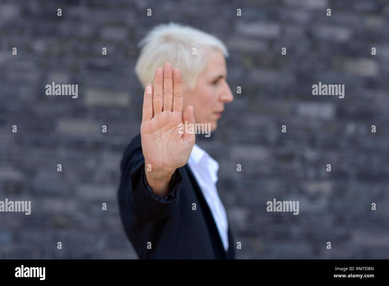Woman making a stop or halt gesture with her hand in a side view focus ...
