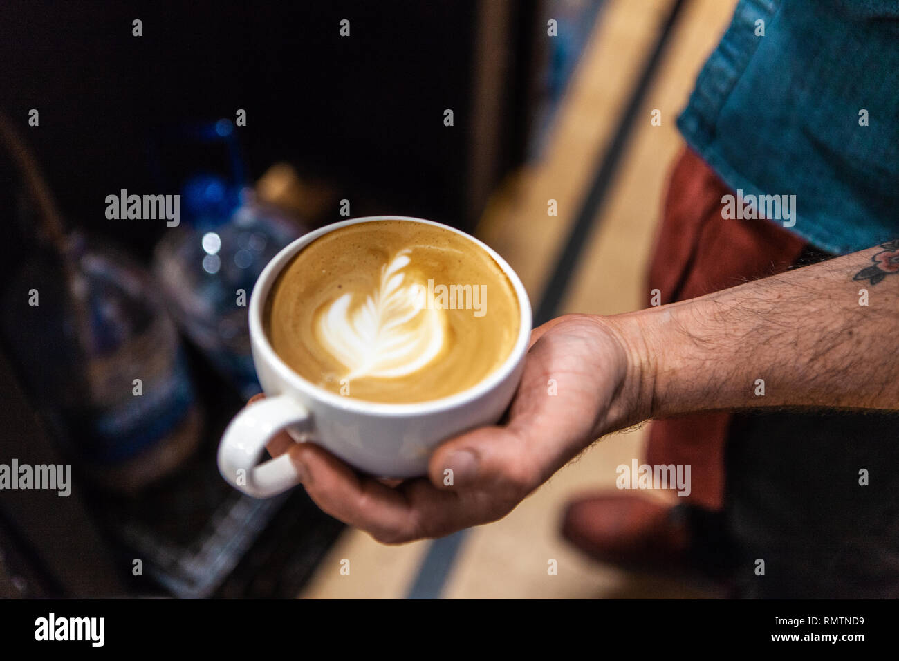 Tattoes waiter shows the camera his free poor latte art Stock Photo - Alamy