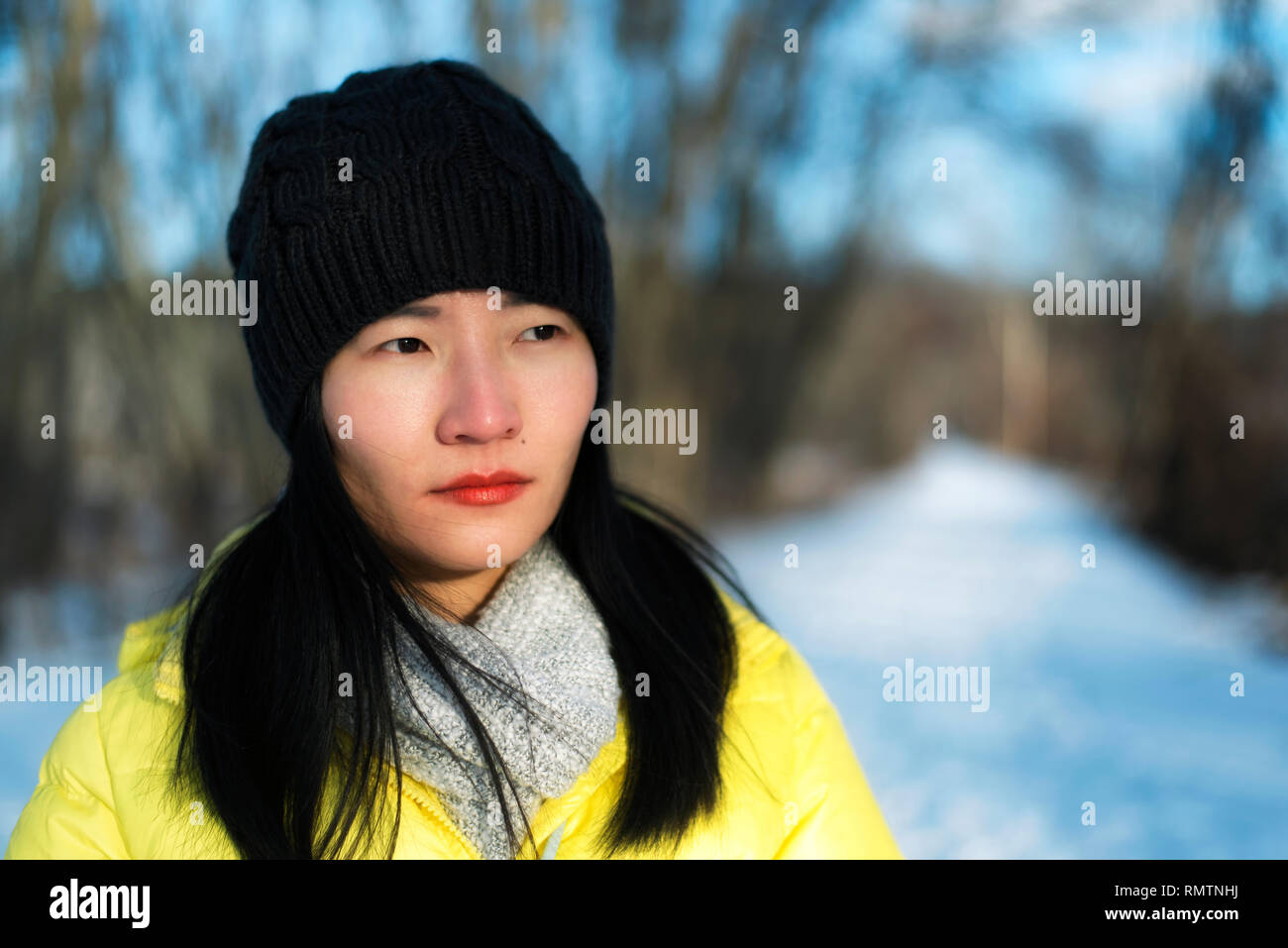 An attractive Chinese woman wearing a yellow winter jacket looking away ...