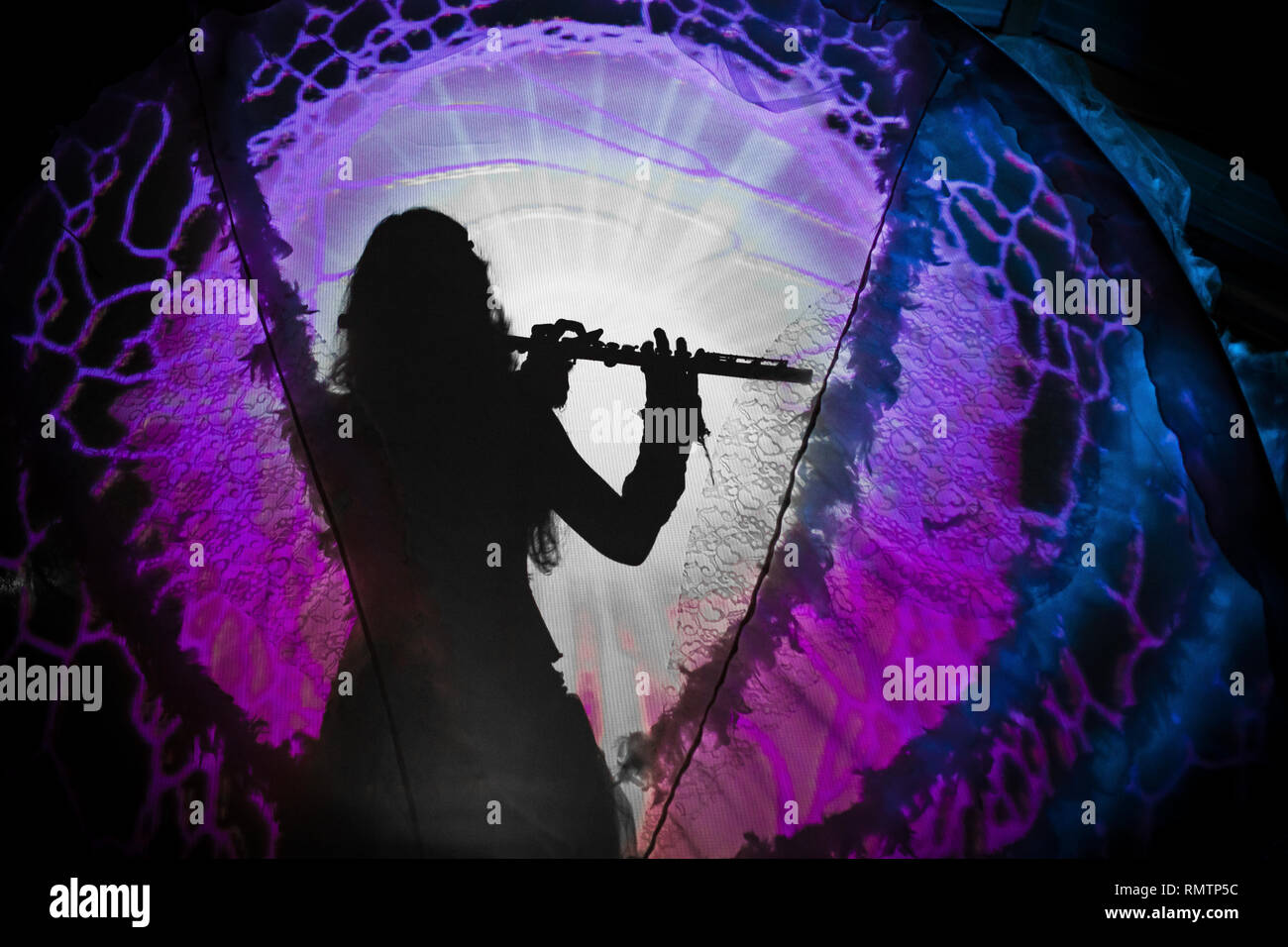 Very sharp shadow of a woman playing flute casted on a psychedelic ...