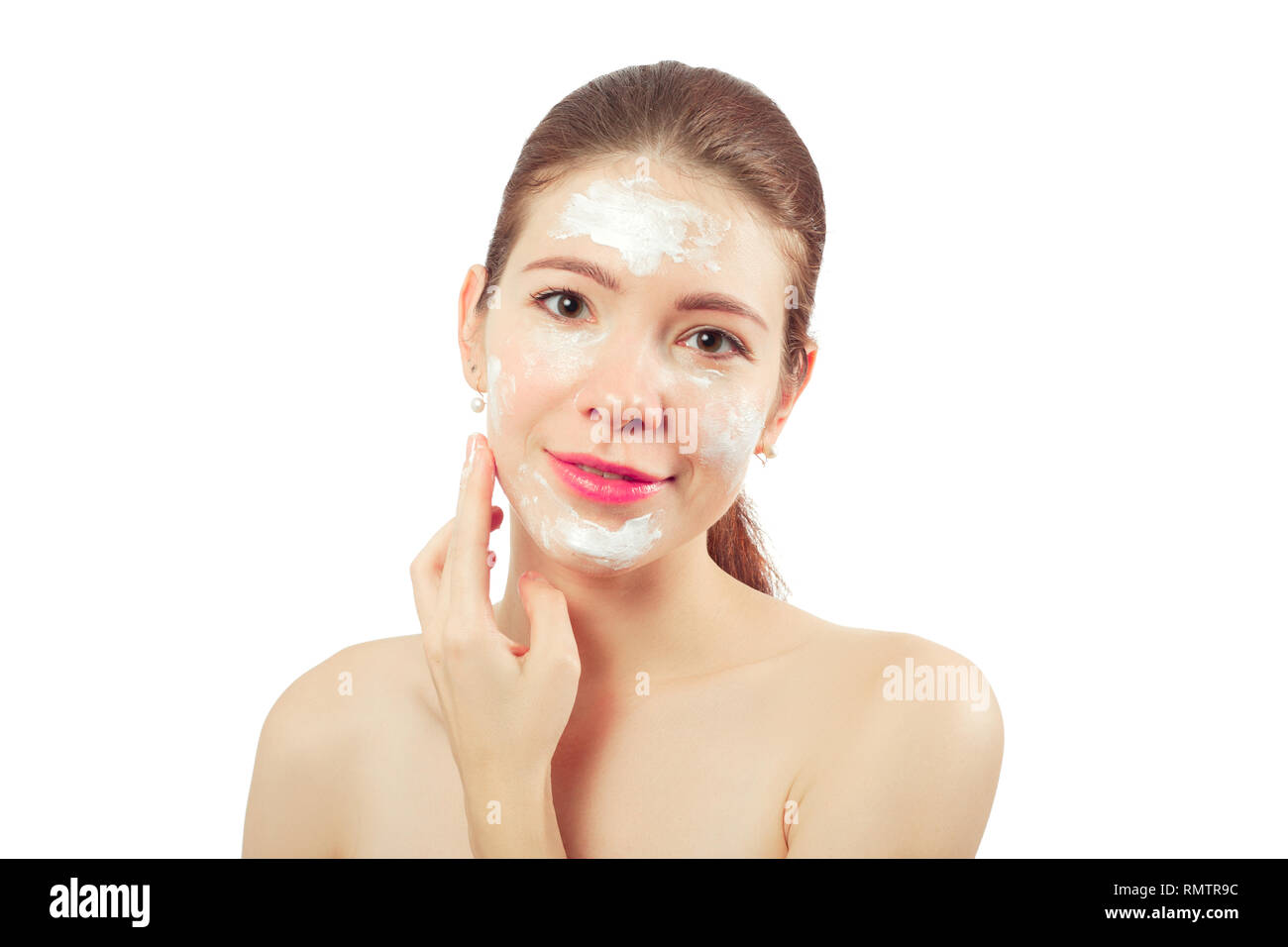 serious young woman applying cream on her face skin, isolated on white ...