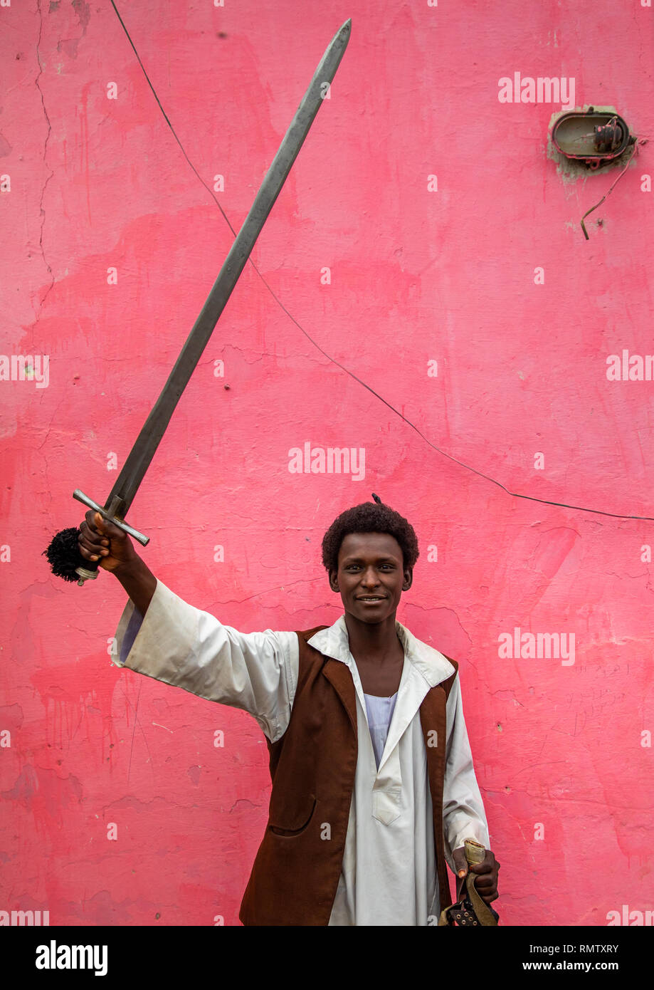 Beja tribe warrior with his sword in front of a pink wall, Red Sea ...