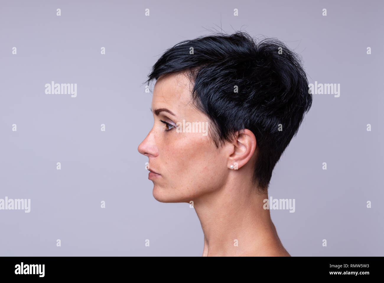 Side view portrait of a woman in short darker hair over neutral ...
