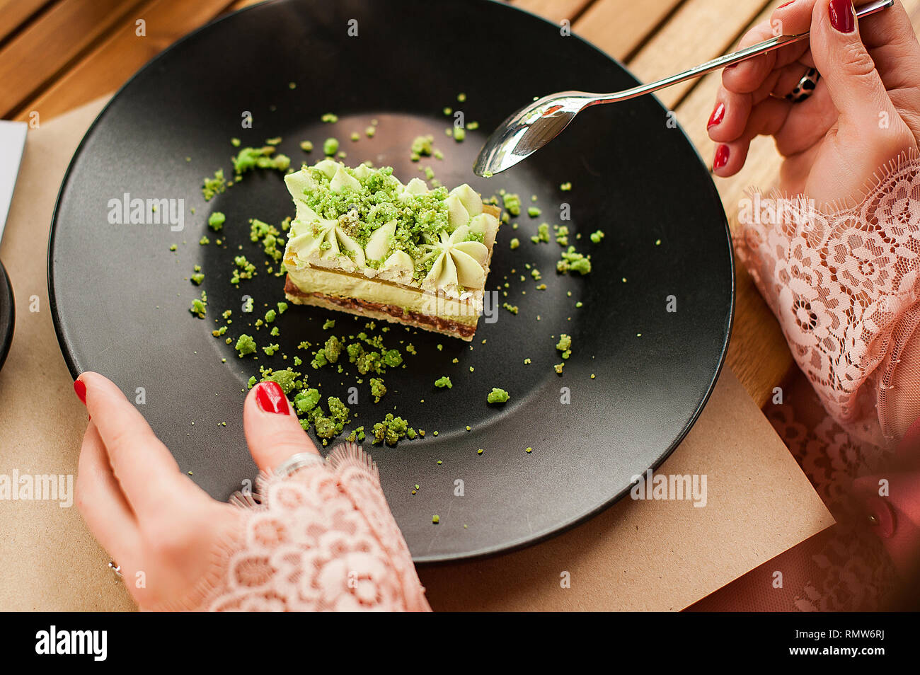 Black plate with a piece of cake. Woman eating cake Stock Photo - Alamy