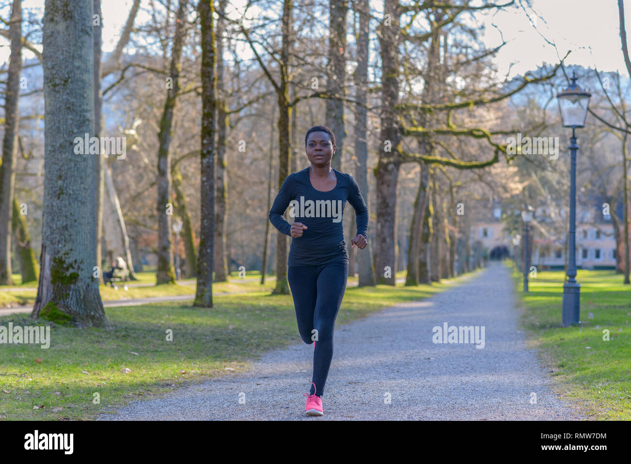 Young African woman jogging during her daily workout running along a ...