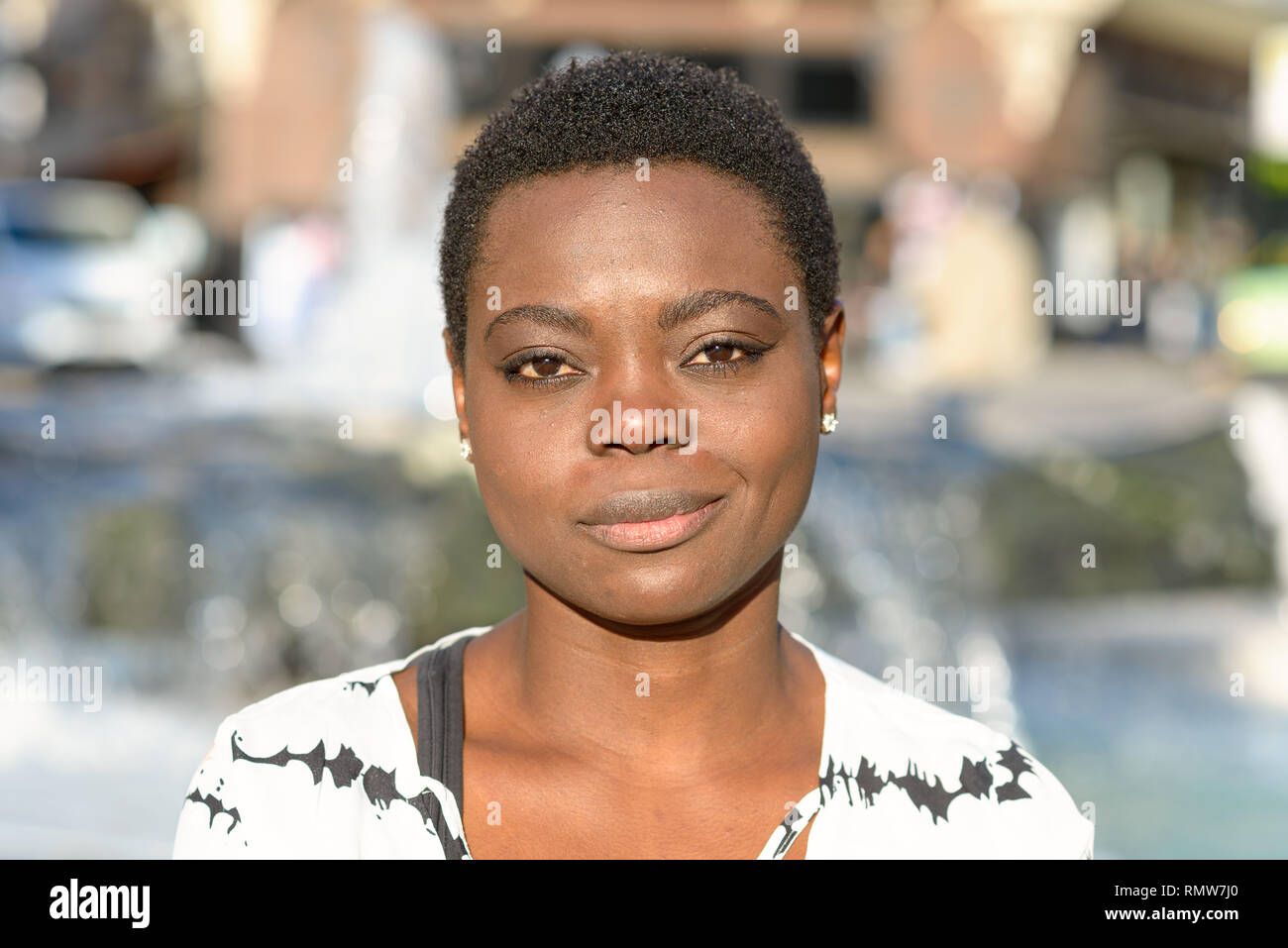 Pretty friendly young African woman giving a quiet smile as she looks ...