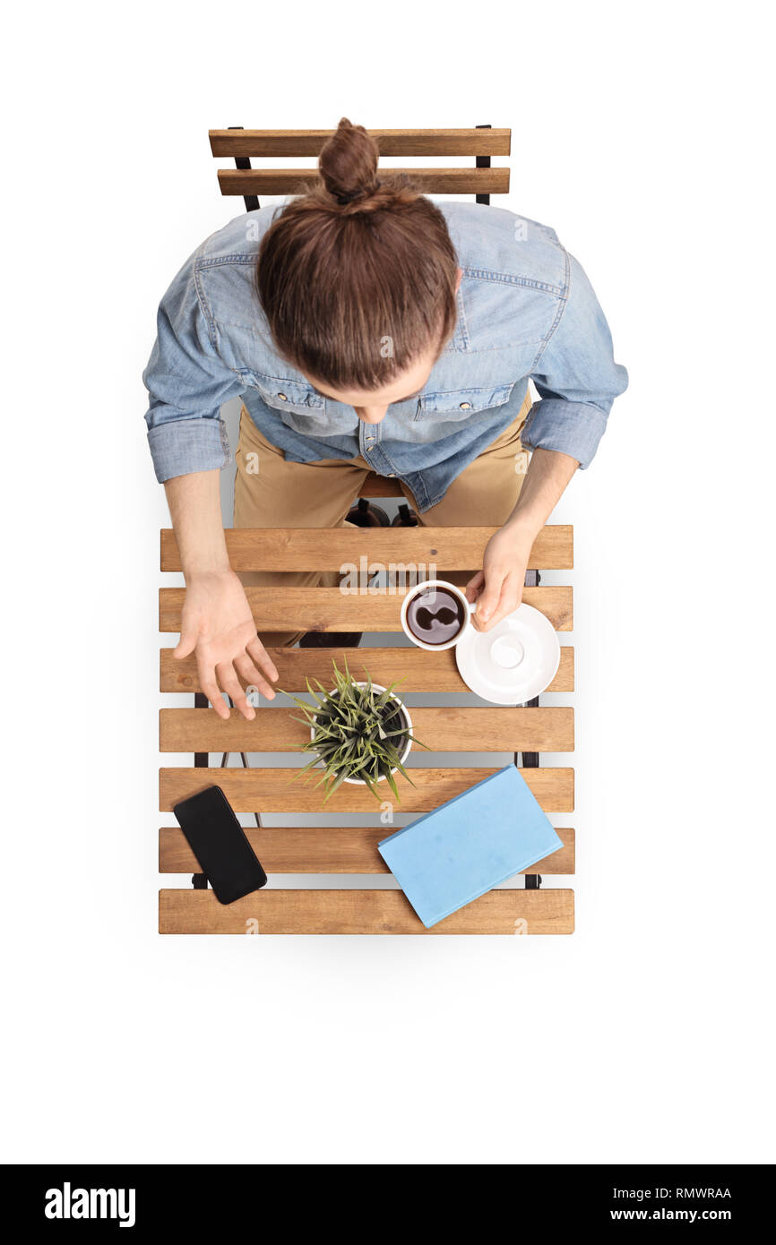 Top view of a young man sitting at a table with a cup of coffee ...