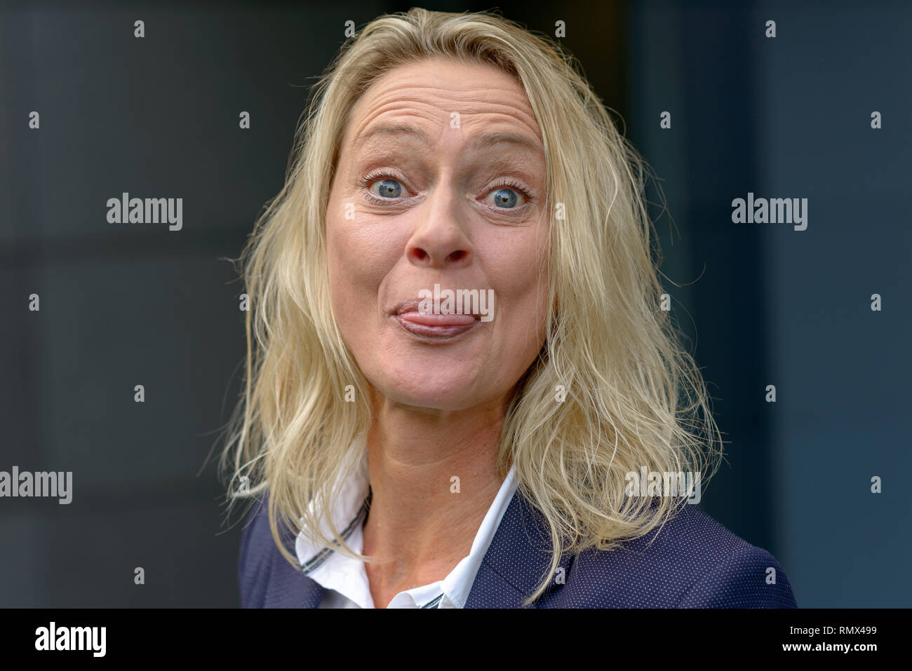 Playful blond woman sticking out her tongue with raised eyebrows and an ...