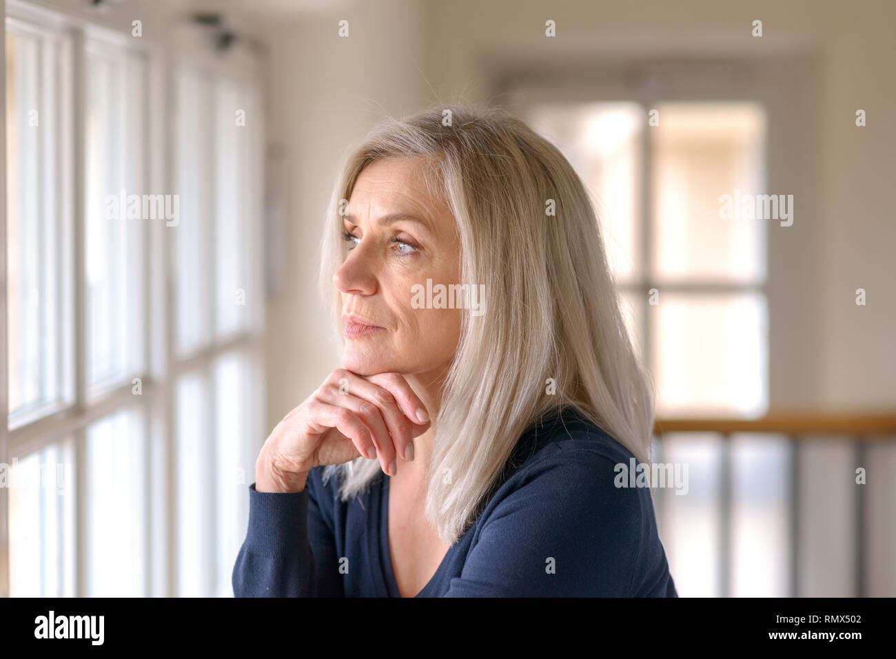 Attractive thoughtful woman with serious expression standing with her ...