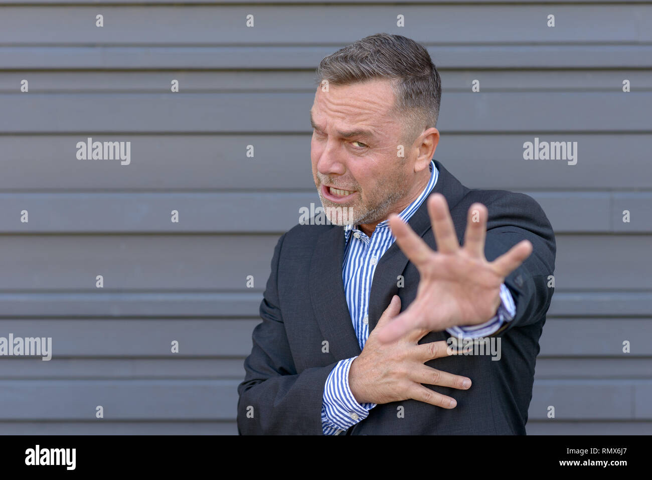 Businessman making a halt gesture with one hand, covering his chest ...
