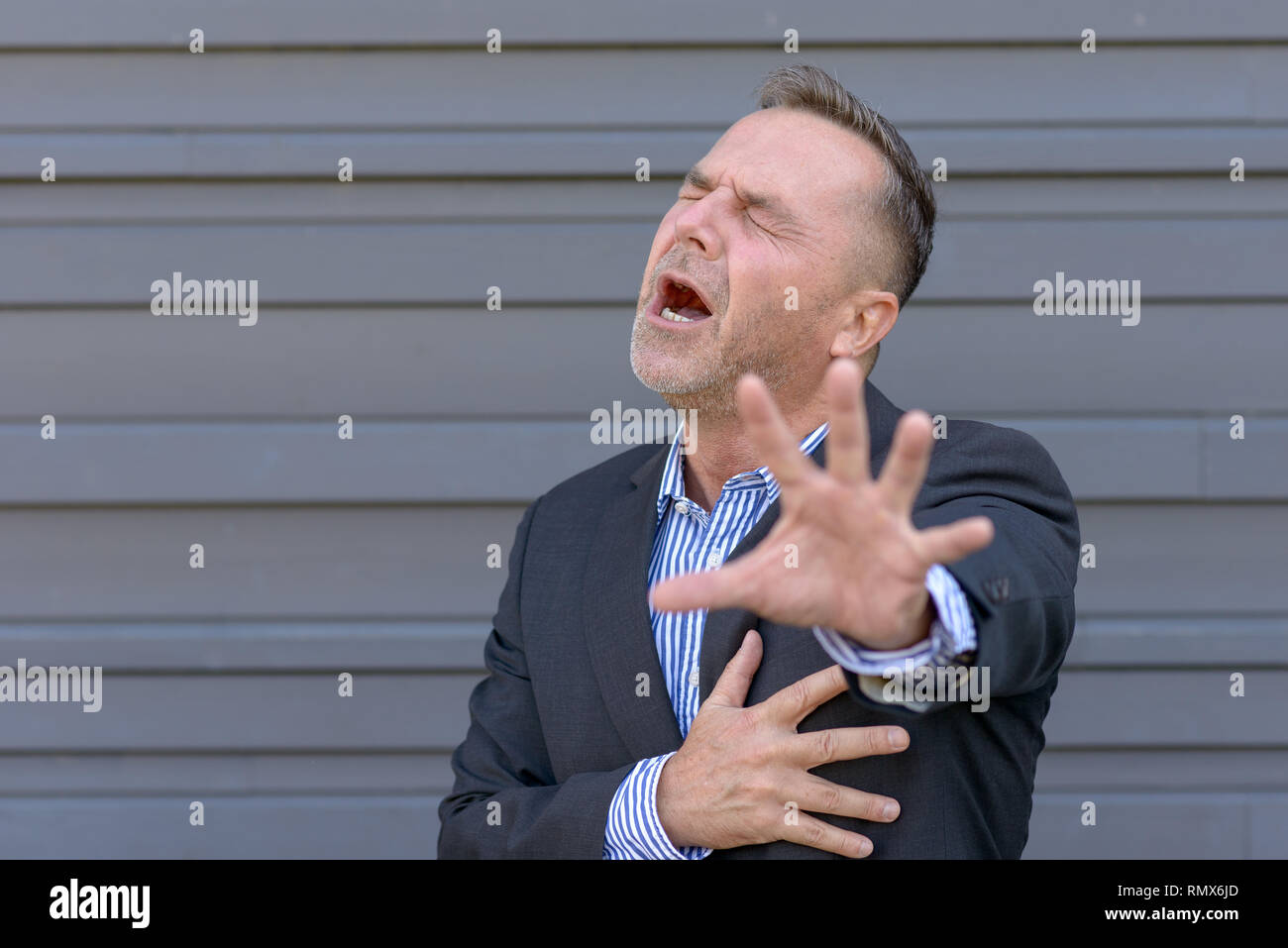 Businessman clutching his chest in pain or anguish while reaching out ...