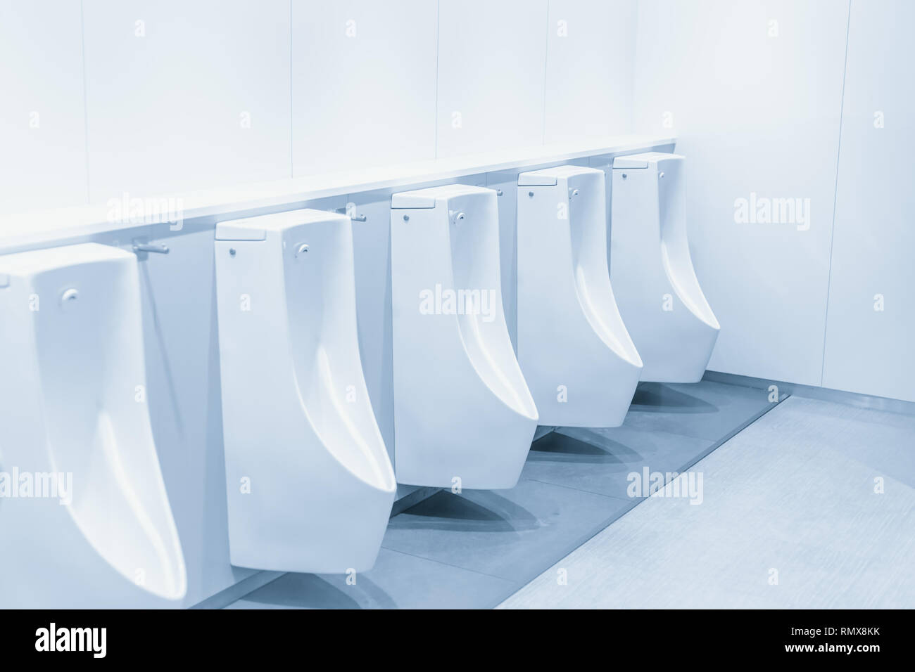 Close up row of urinal toilet blocks in public restroom clean blue ...