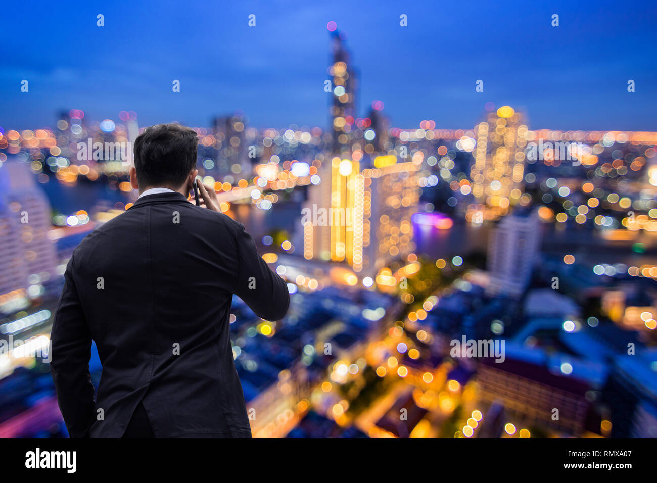 businessman calling phone on top of tower with night city background ...
