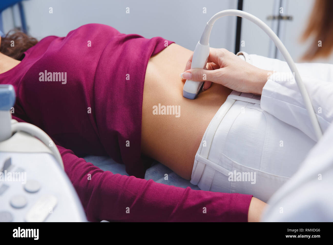 female doctor operating ultrasound scanner examining belly of her ...