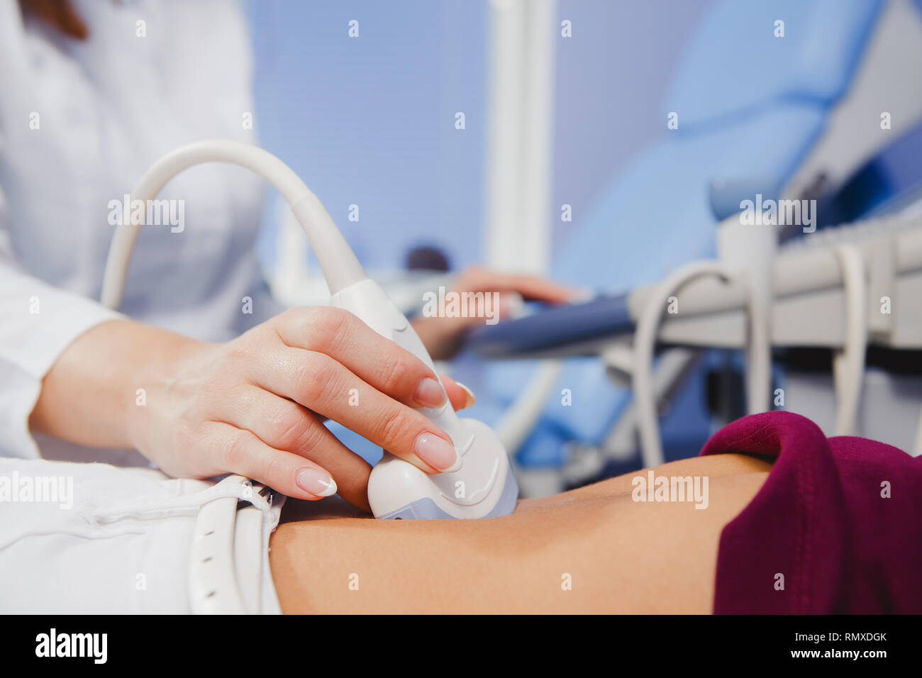 female doctor operating ultrasound scanner examining belly of her ...