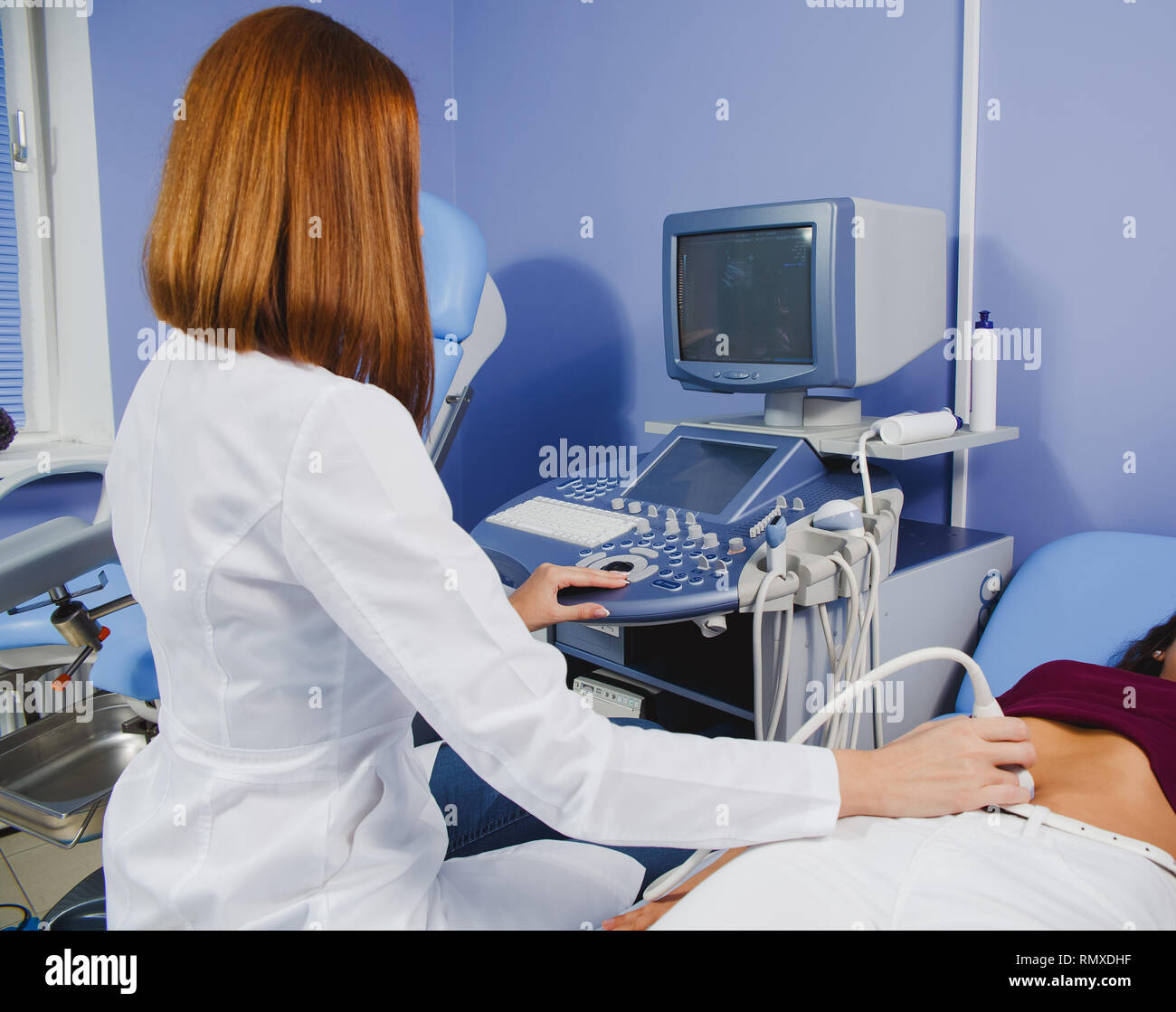female doctor operating ultrasound scanner examining belly of her ...