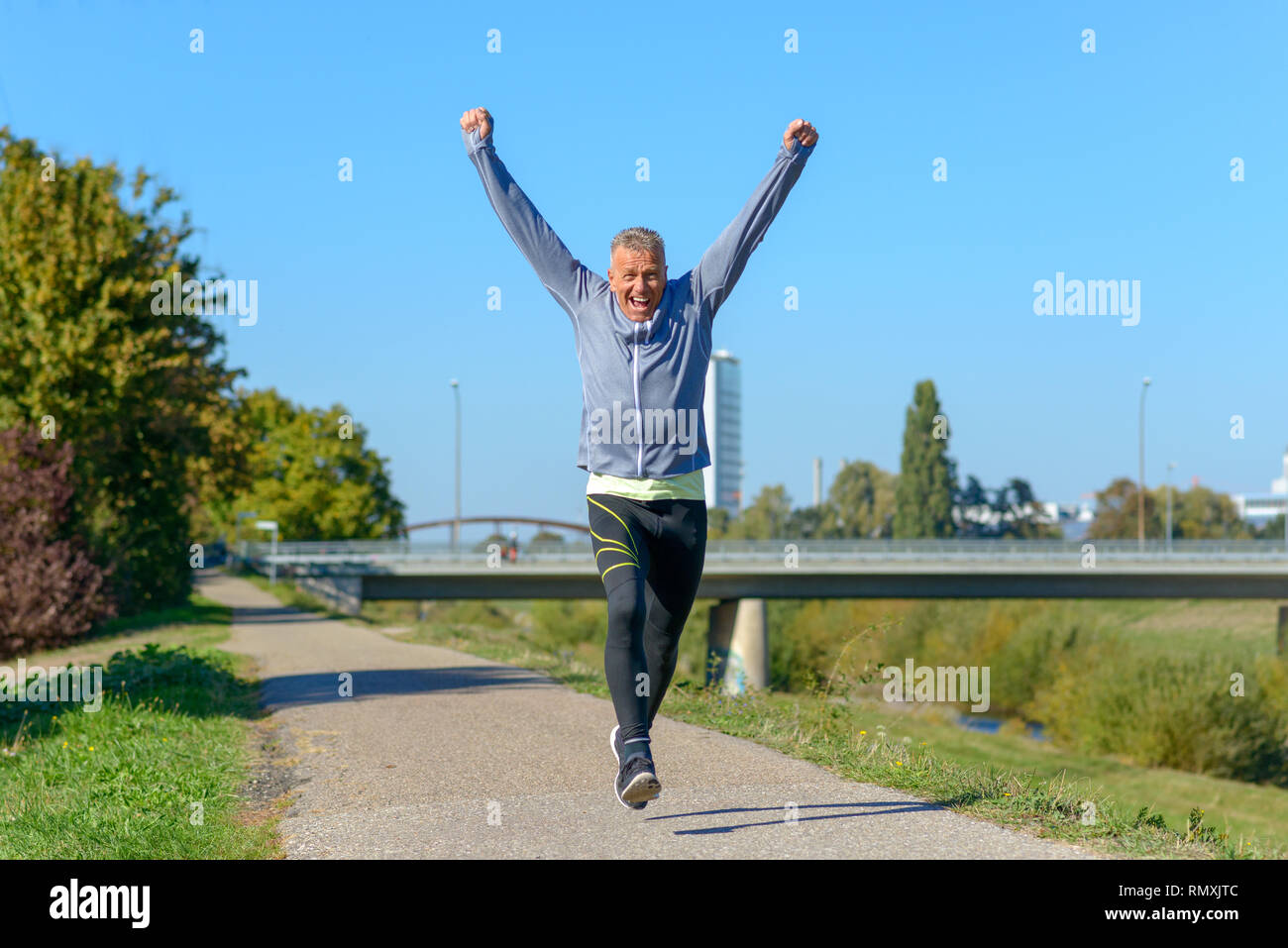 Happy fit middle aged man cheering and celebrating as he walks along a ...