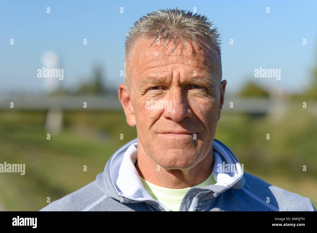 Serious man with an inscrutable expression standing in a park staring ...