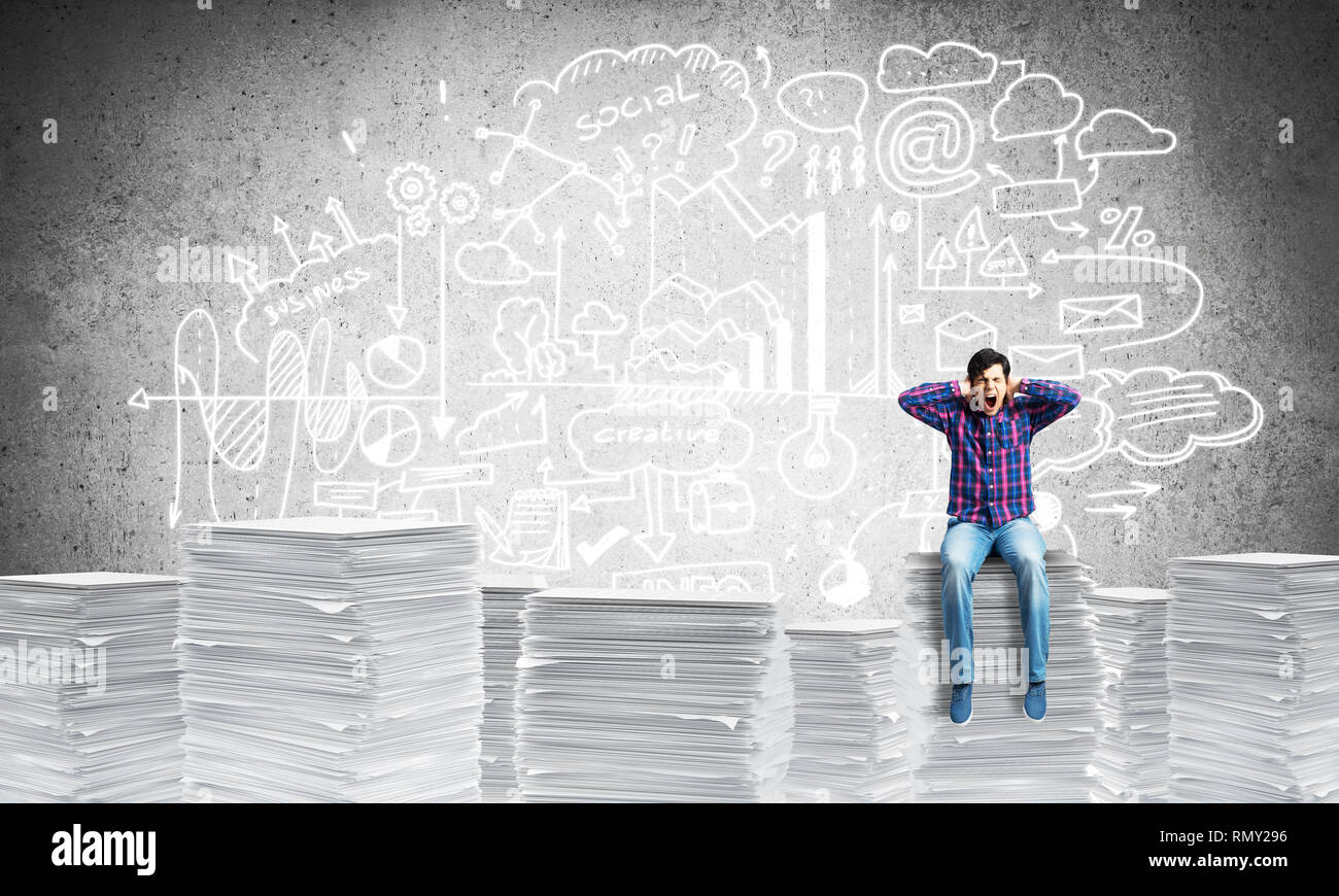 Attractive man sitting on pile of paper documents Stock Photo - Alamy