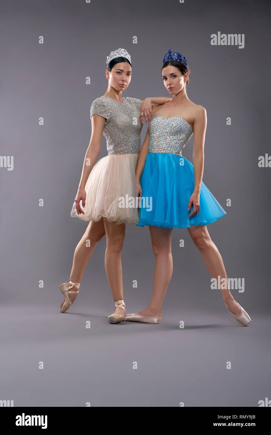 Young attractive ballet dancers standing together in studio, looking at ...