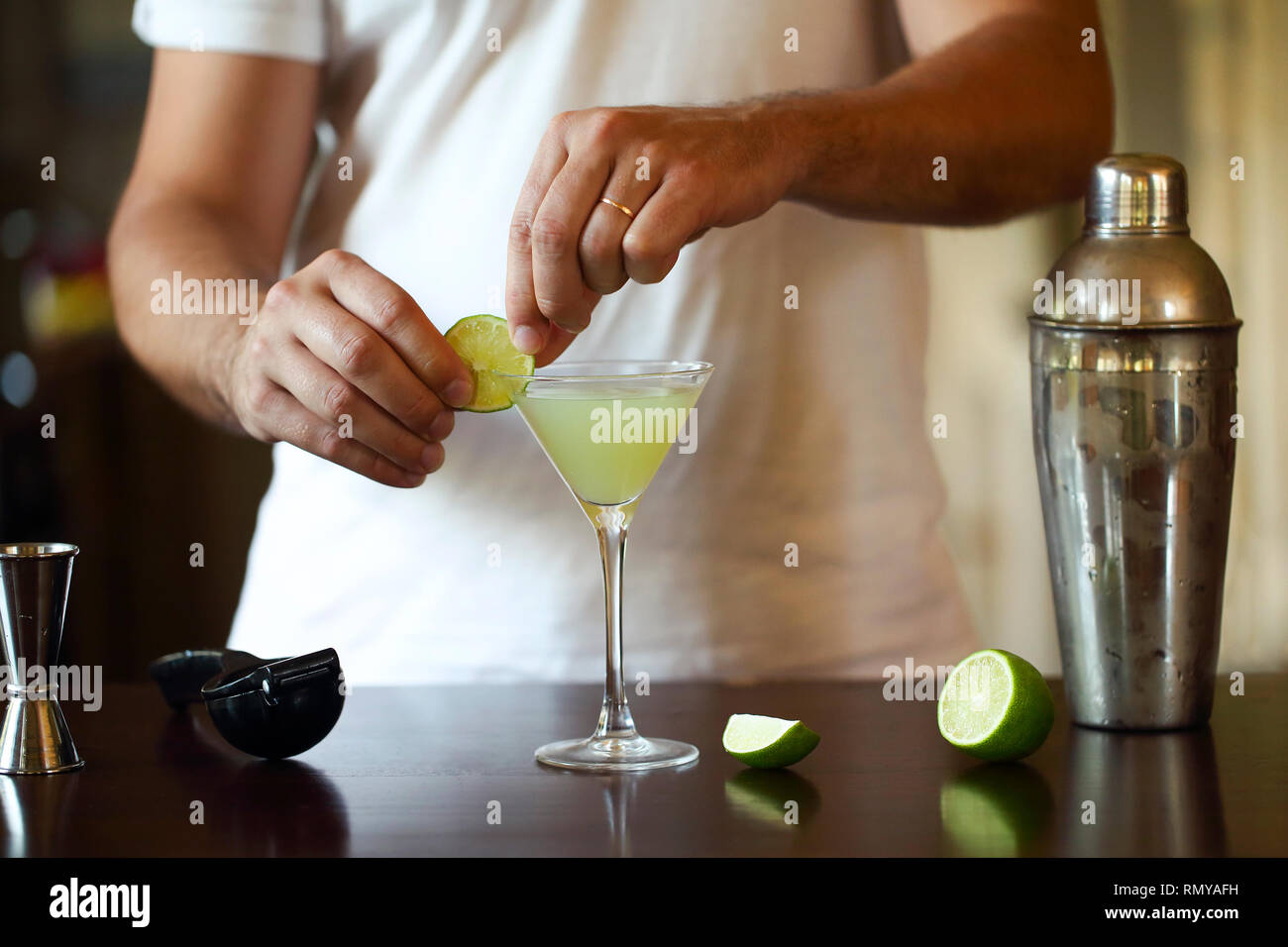 Barman at work, preparing cocktails. Pouring martini to cocktail glass ...