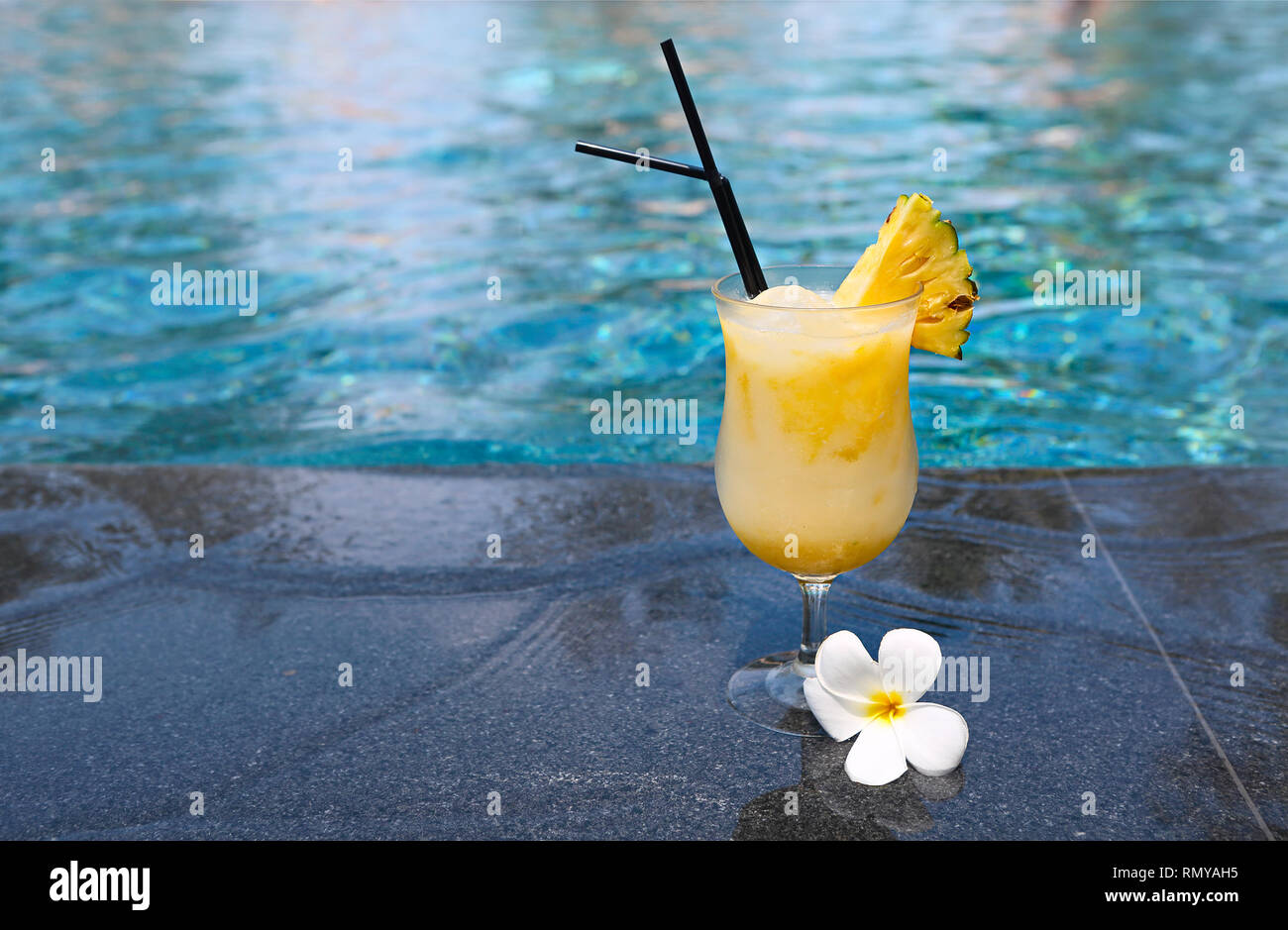 Glass of pinacolada cocktail standing on the swimming pool ledge in an ...