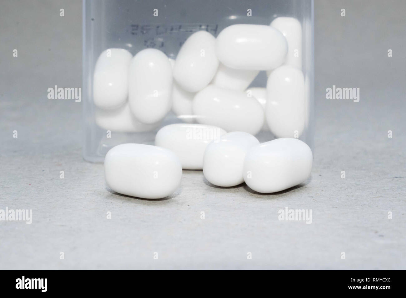 Group of White capsules on the table and on the transparent container ...