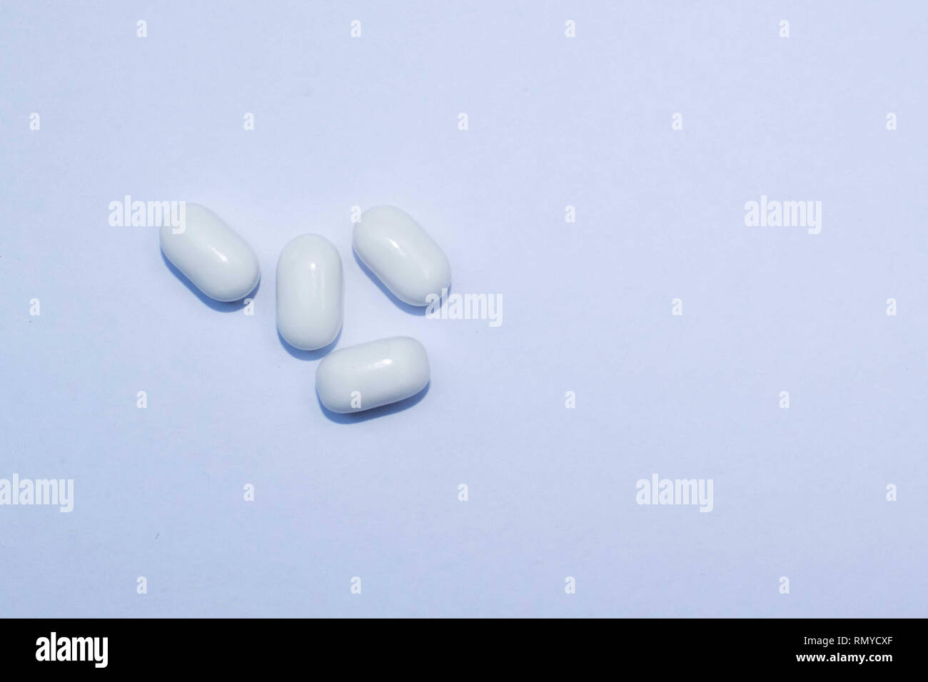 Three white capsules on white background Stock Photo - Alamy