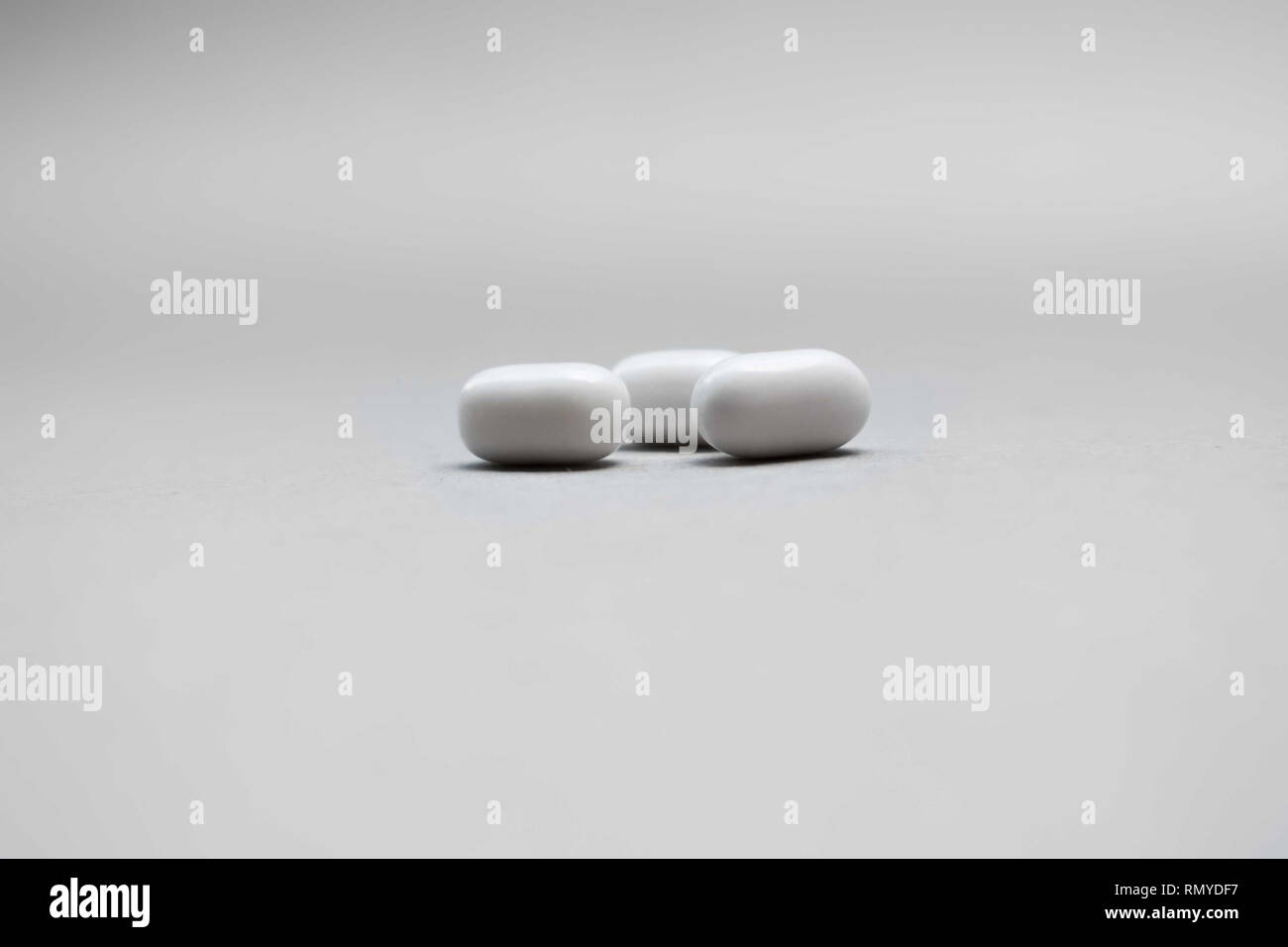 Three white capsules or medicine on white background Stock Photo - Alamy