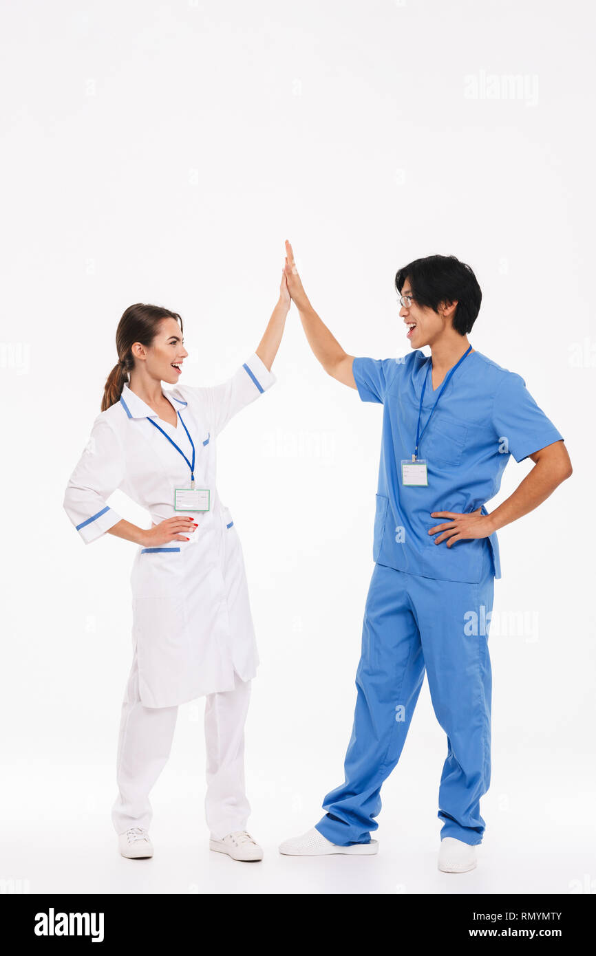 Happy doctors couple wearing uniform standing isolated over white ...