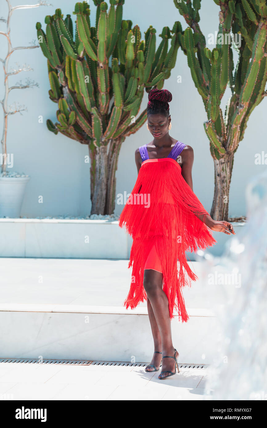 Attractive black woman wearing coral fringed dress walks the runway ...