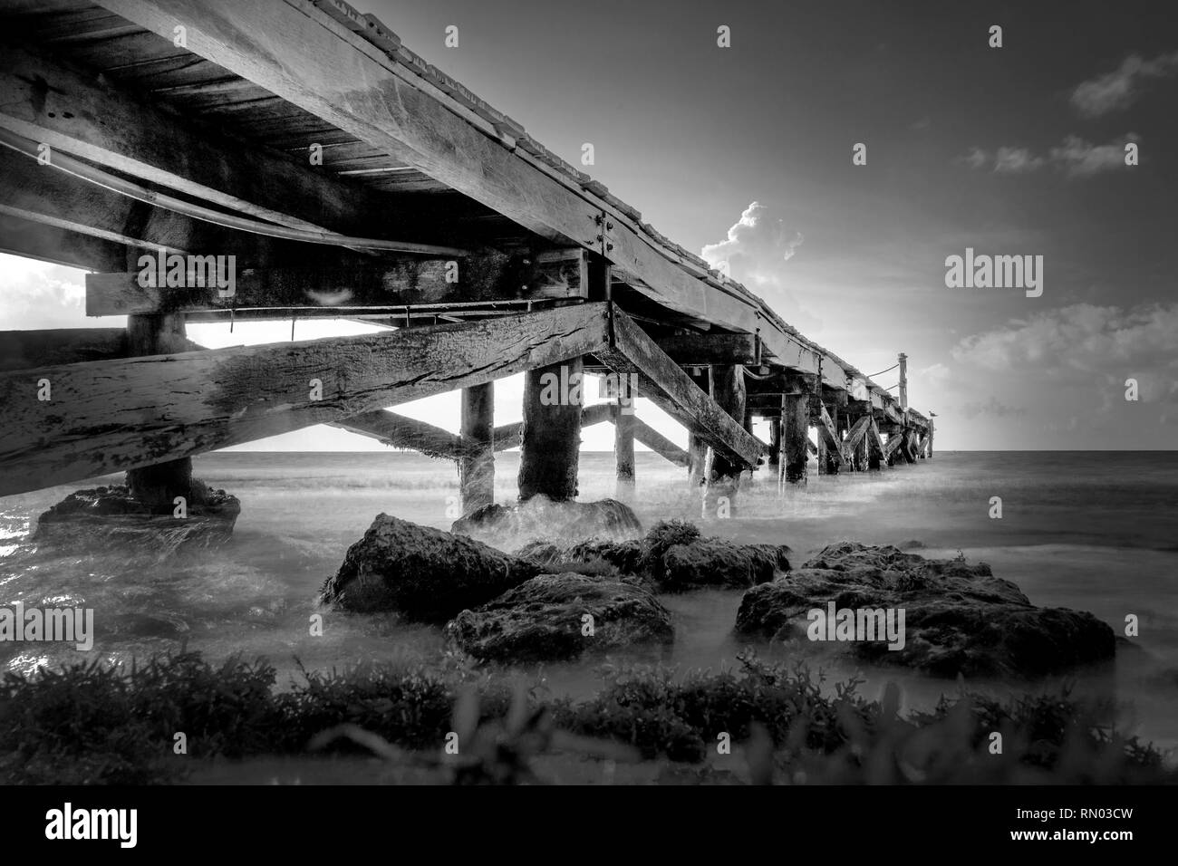Calm scene of abandoned old rustic wooden jetty out to the sea during a ...
