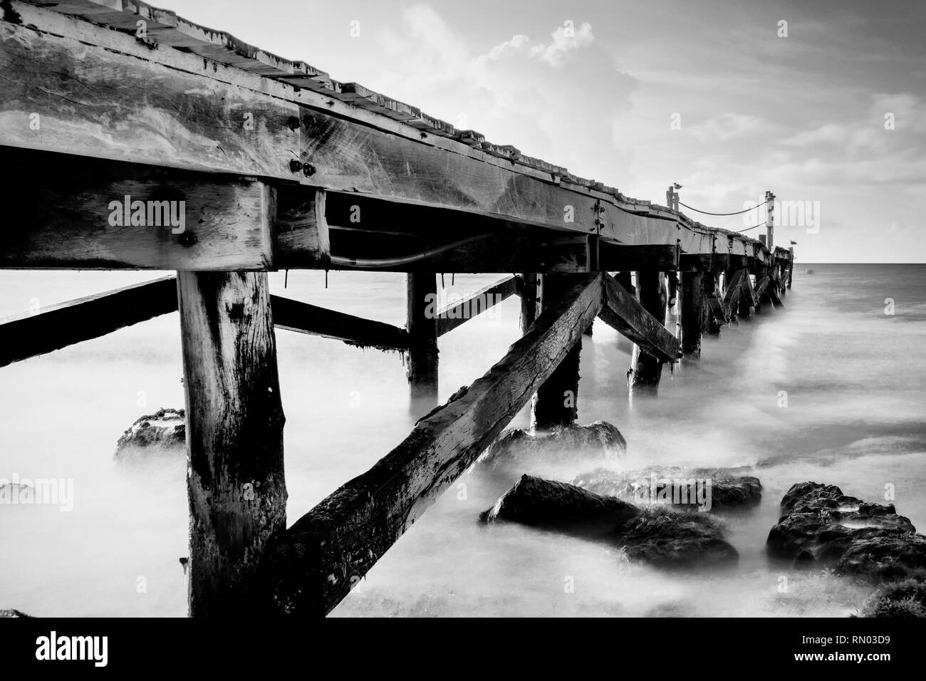 Calm scene of abandoned old rustic wooden jetty out to the sea during a ...