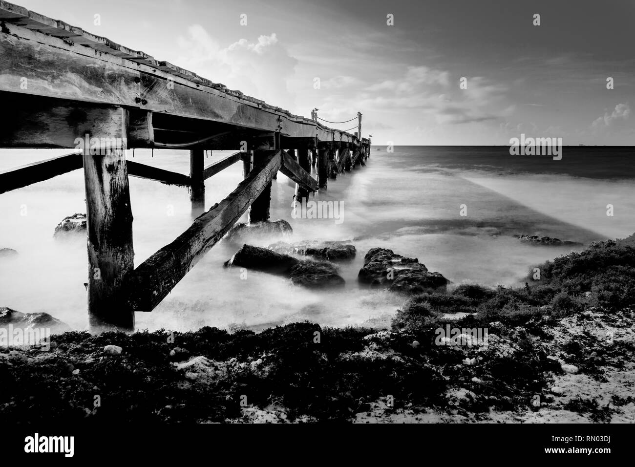 Calm scene of abandoned old rustic wooden jetty out to the sea during a ...