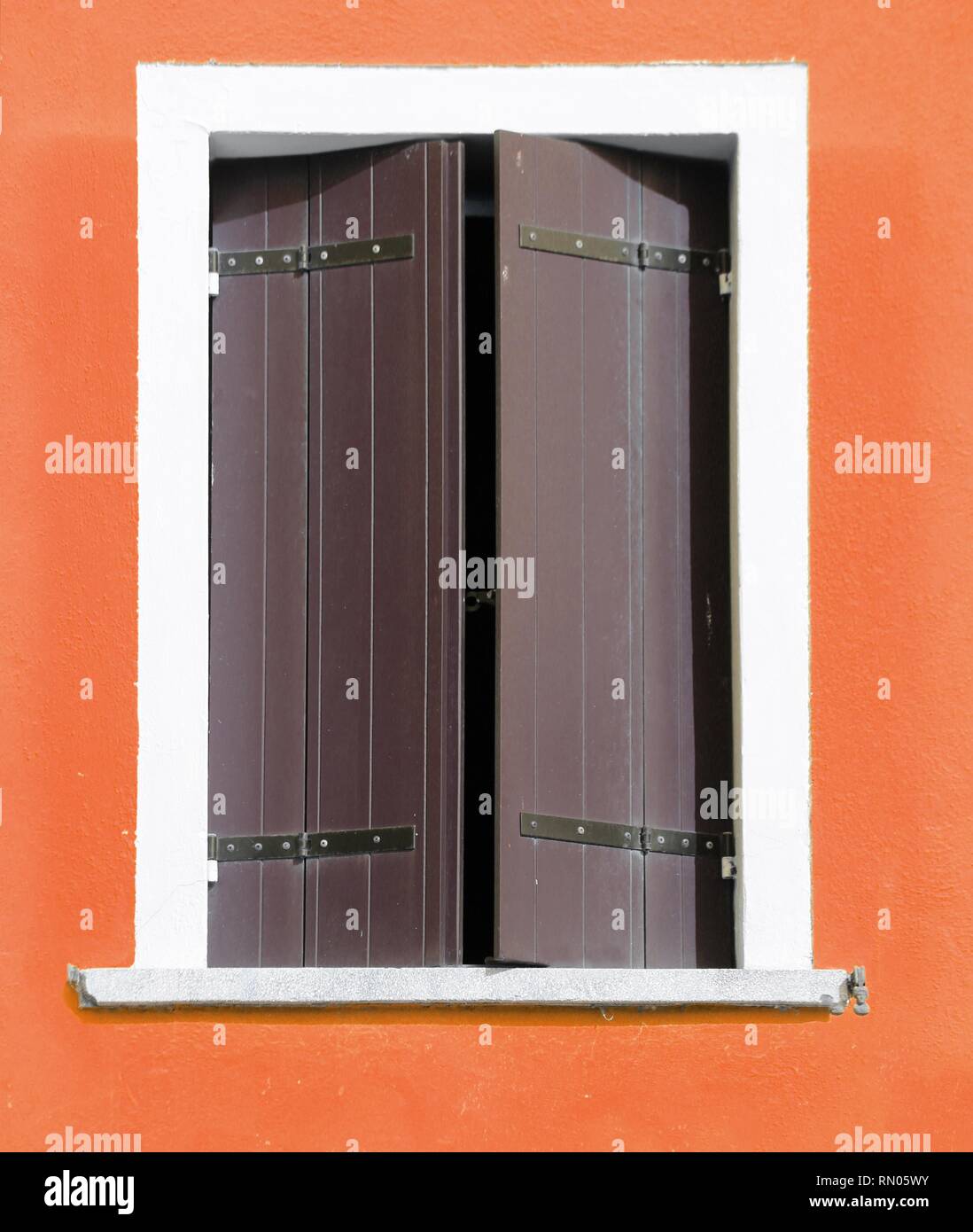 single rectangular window with closed shutters and orange wall Stock ...