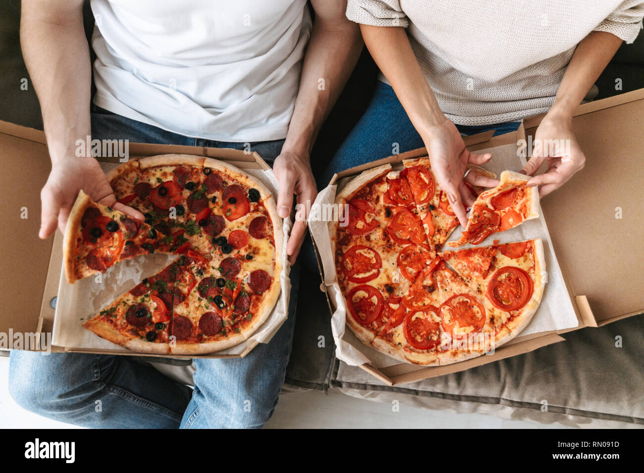 Top view of a couple eating two big pizzas on a couch Stock Photo - Alamy