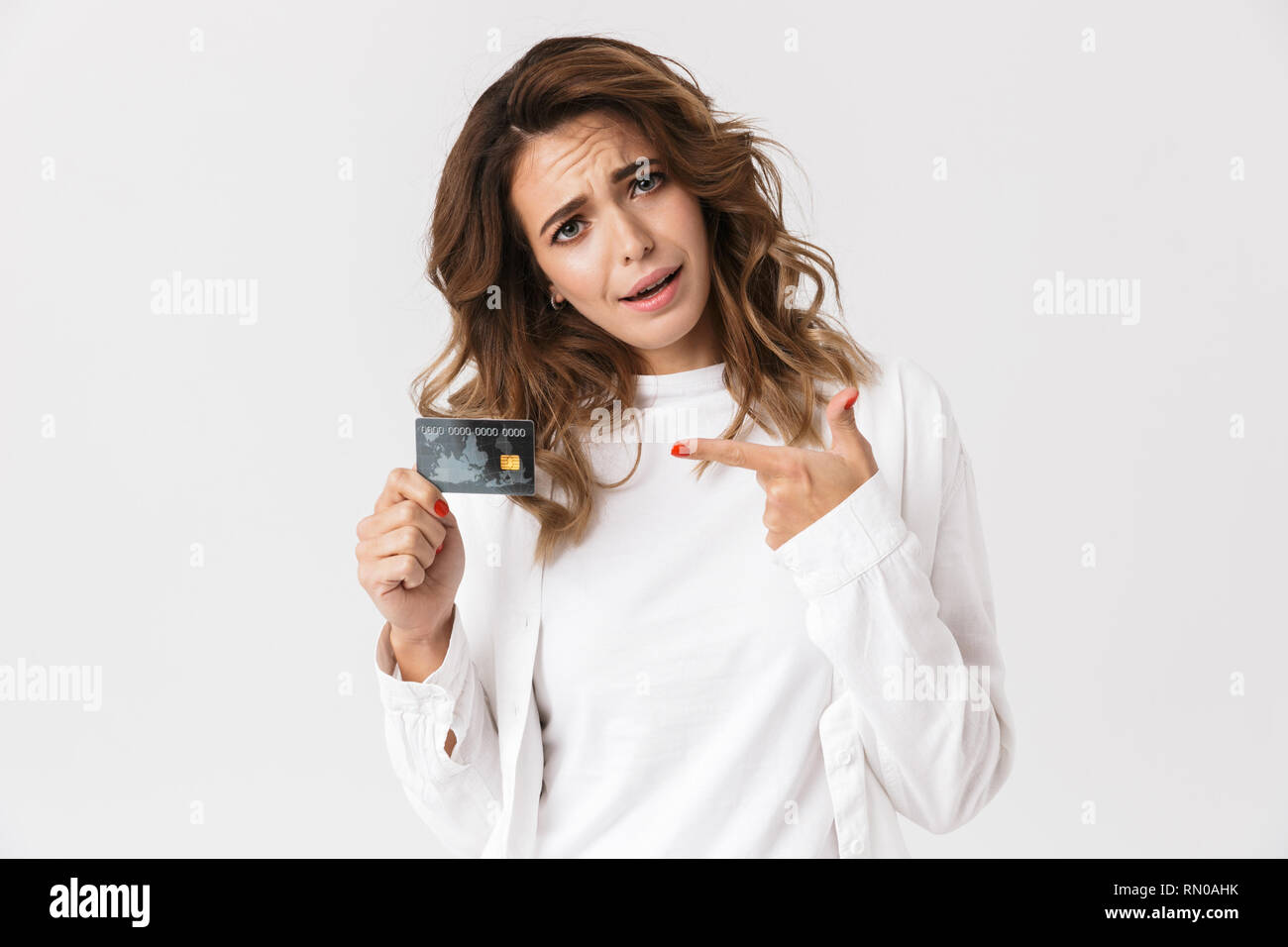 Confused young woman showing plastic credit card isolated over white ...