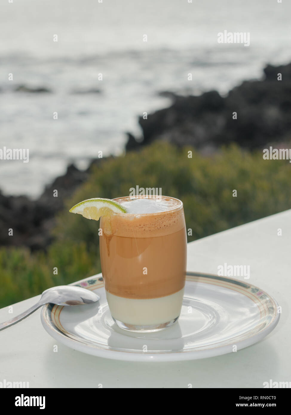 Coffee with milk, with Atlantic ocean and volcanic coastline background ...