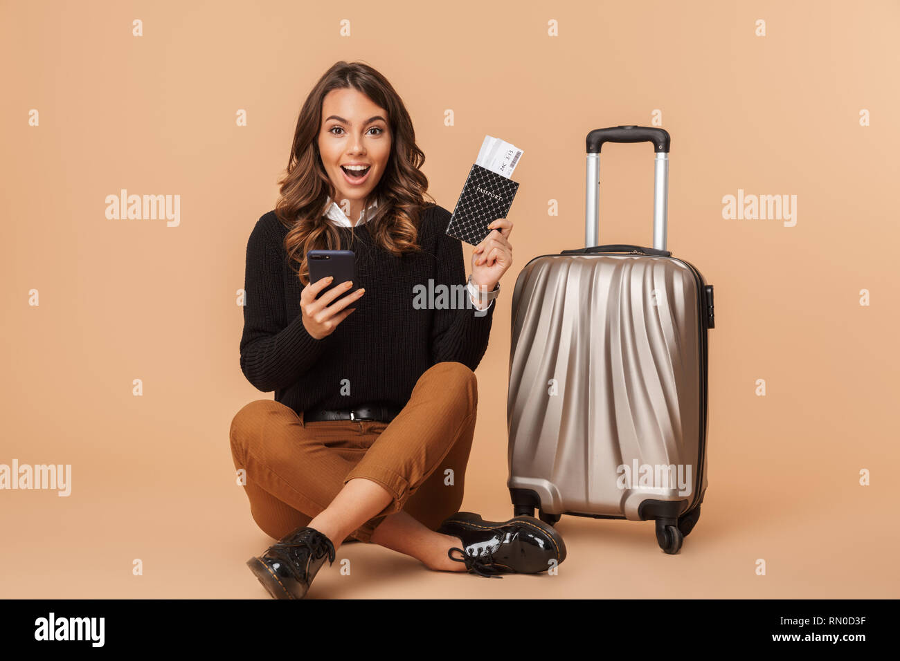 Elegant woman with baggage holding smartphone and travel ticket while ...