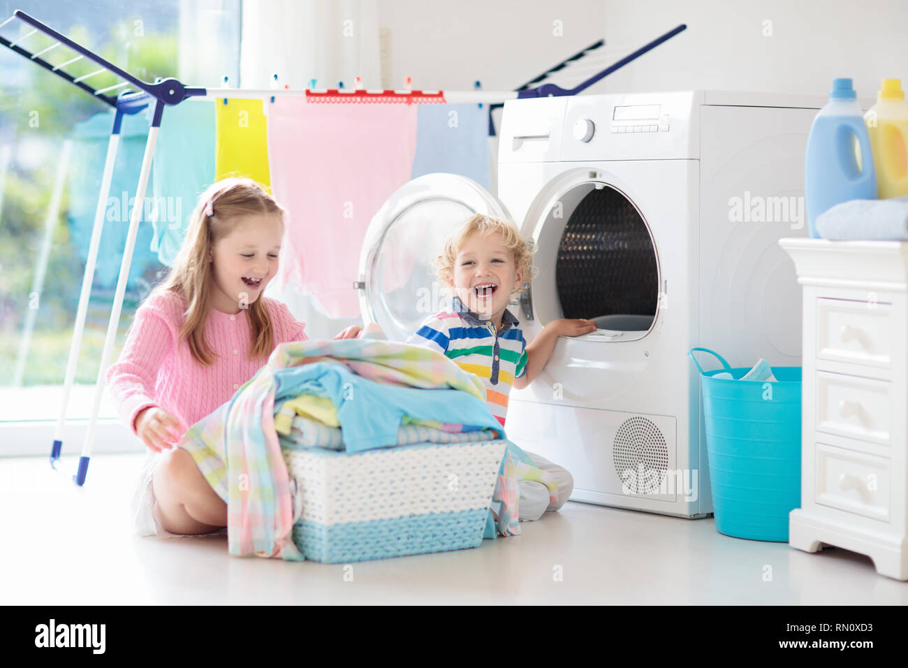 Children in laundry room with washing machine or tumble dryer. Kids ...