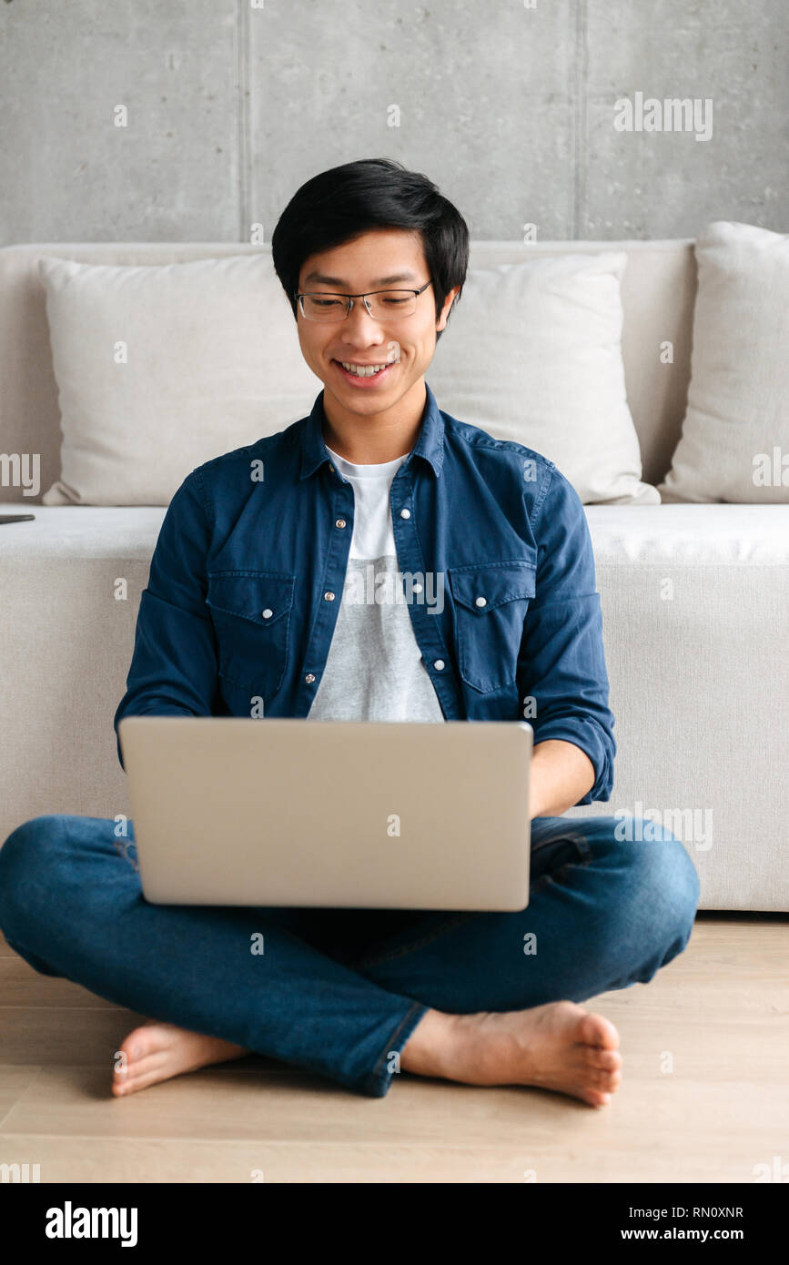 Happy asian man sitting at a couch at home, using laptop computer Stock ...