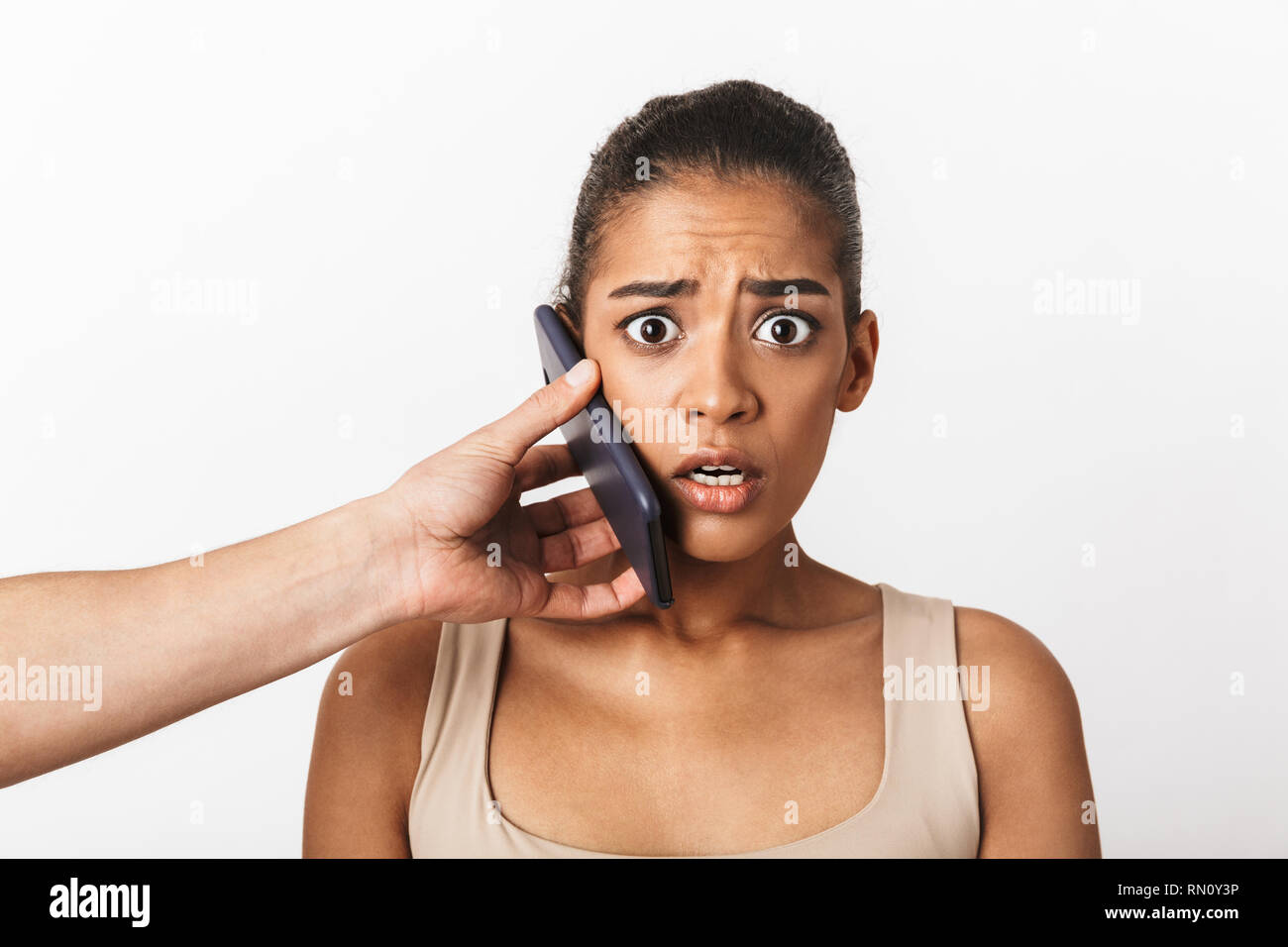 Scared young african woman sitting while man's hand holding mobile ...