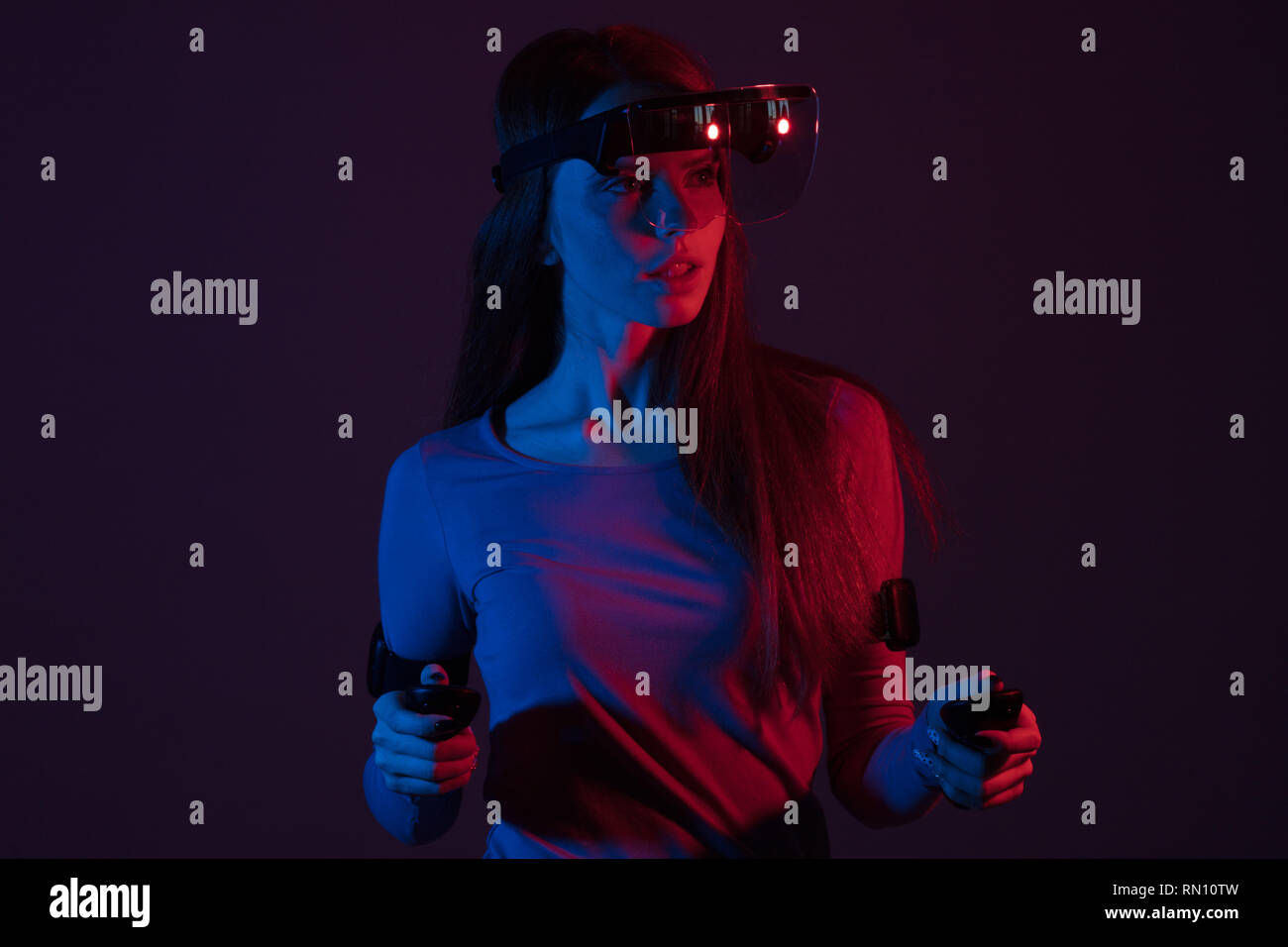 Woman prepare to VR game in studio with red and blue colour lights dark ...
