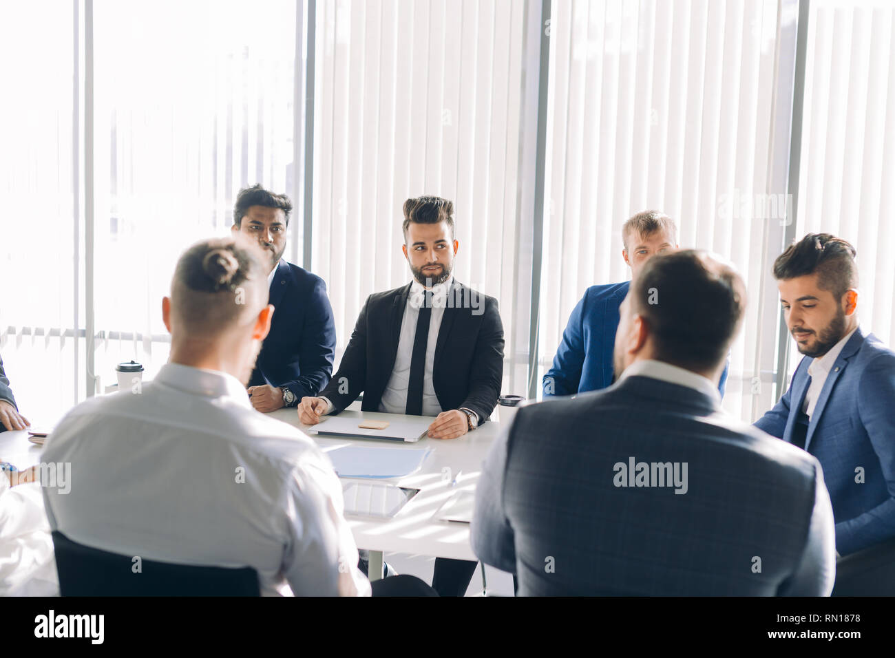 Multiracial male business executives discussing project sitting at ...