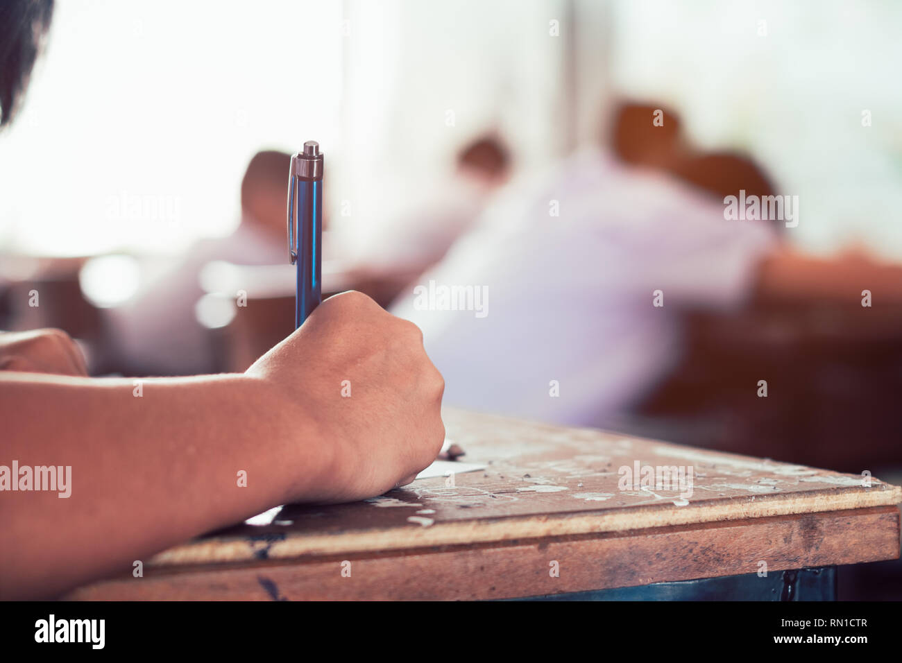 Close-up to student holding pen and writing final exam in examination ...