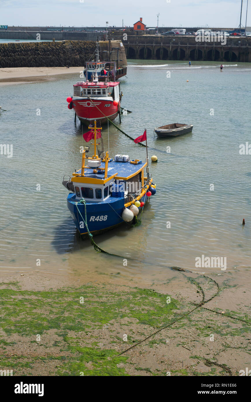 Red and blue fishing trawlers at low tide Stock Photo - Alamy