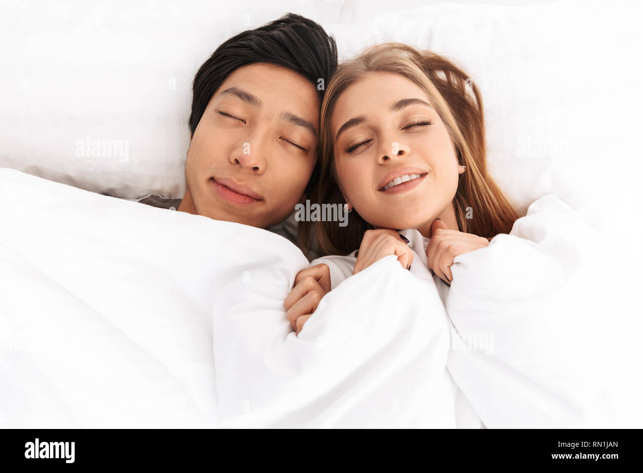 Happy young couple laying in bed, eyes closed Stock Photo - Alamy
