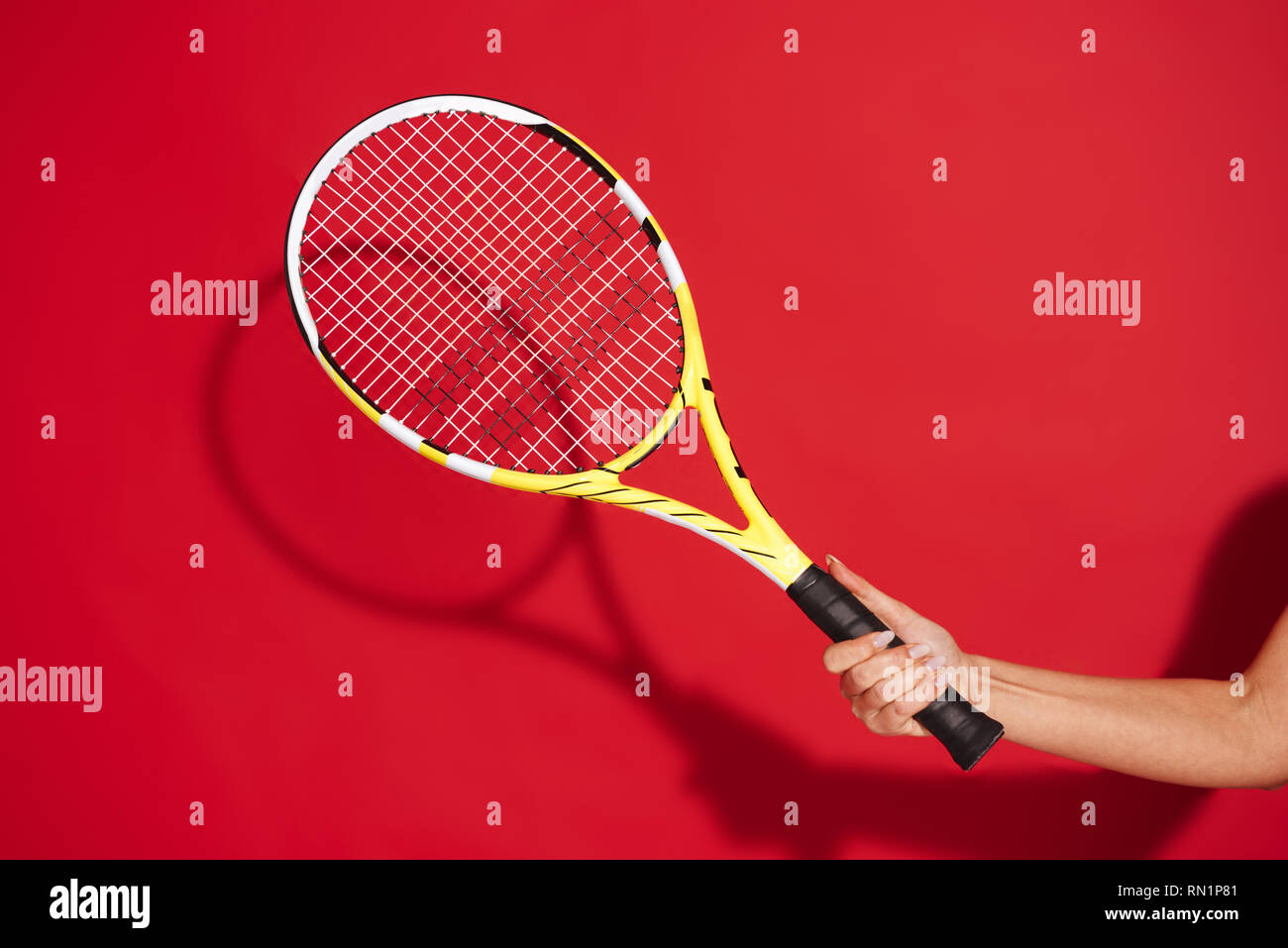Woman's hand holding tennis racket over red background Stock Photo - Alamy