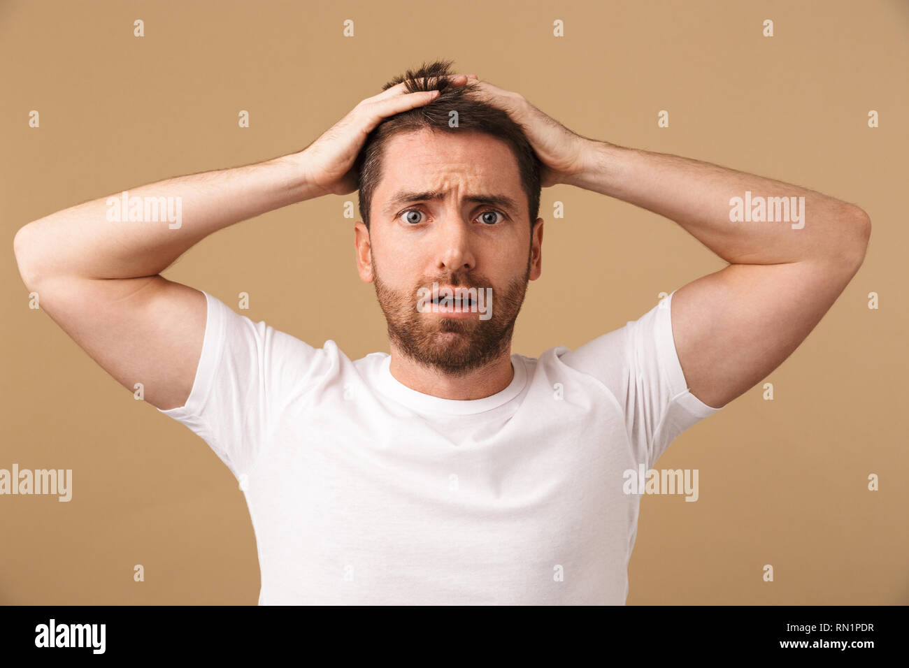 Portrait of a confused young man casually dressed standing isolated ...